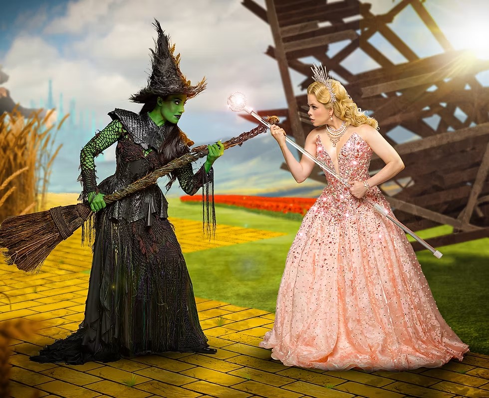 Personagens-Elphaba-e-Glinda-frente-a-frente-no-palco-diante-do-cenario ...